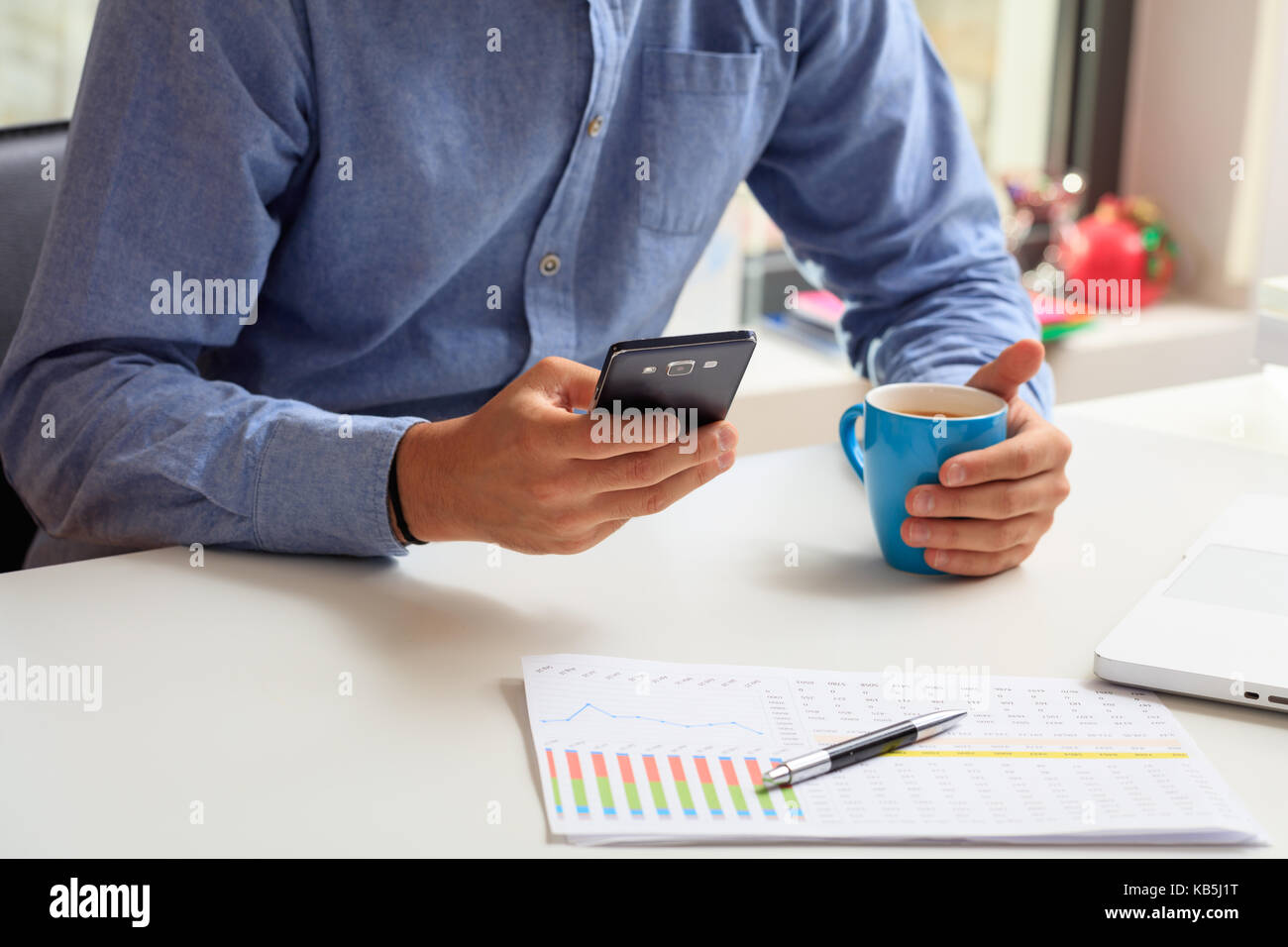 Man holding a smartphone in an office background Stock Photo - Alamy