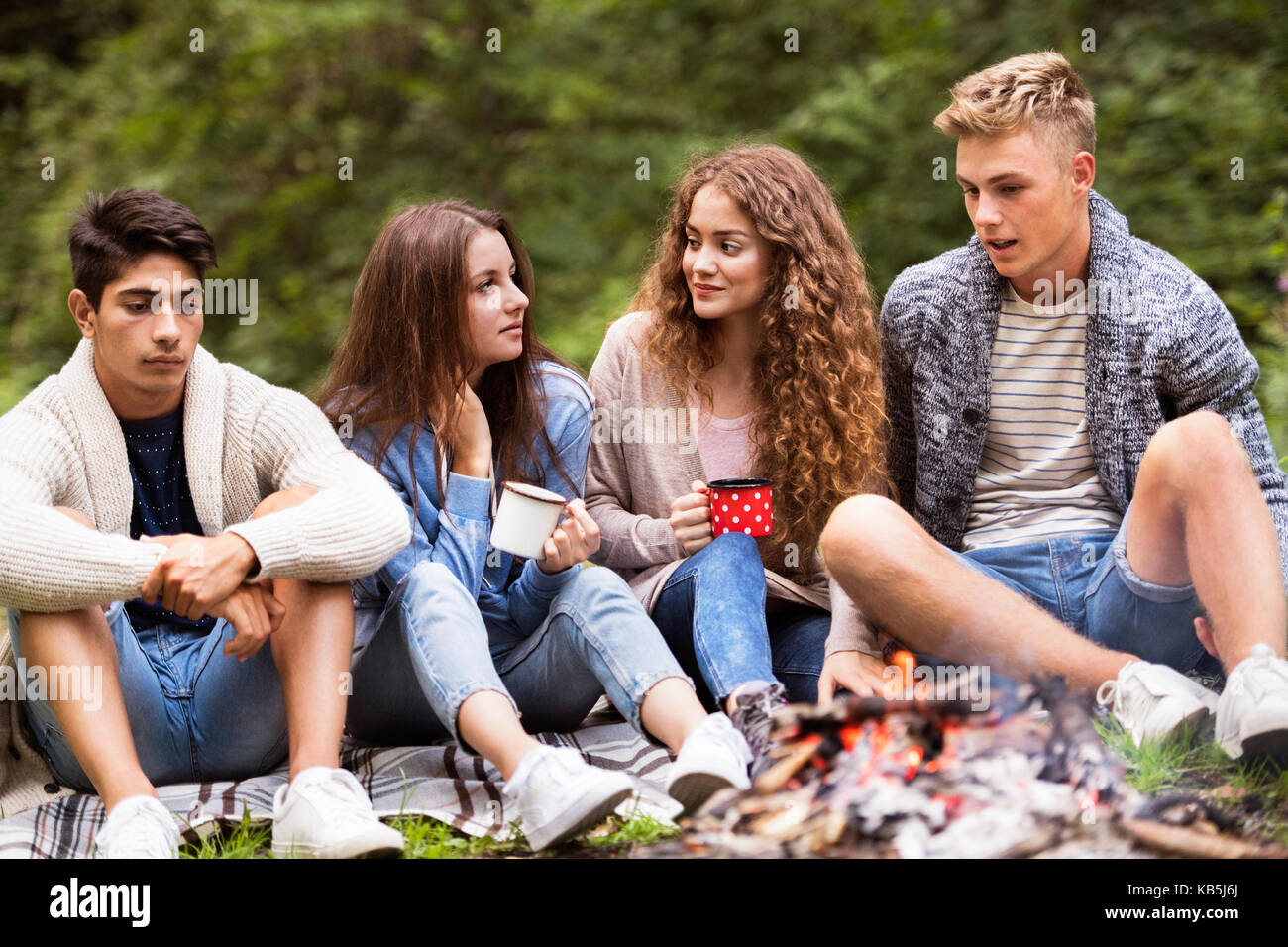 Teenagers camping in nature, sitting at bonfire Stock Photo - Alamy