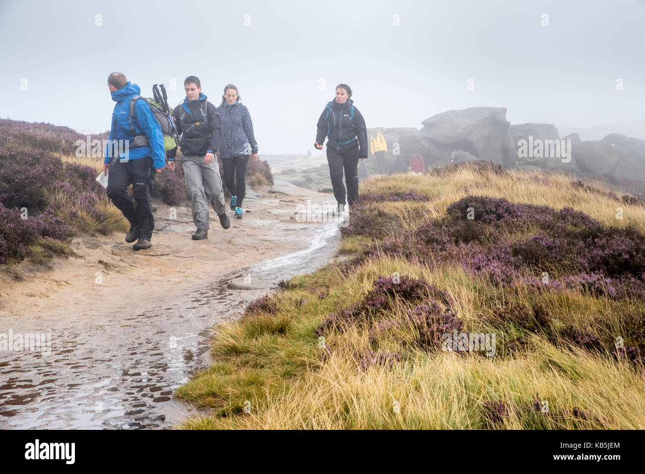 Walkers in fog and wet weather walking a path on moorland of Kinder ...