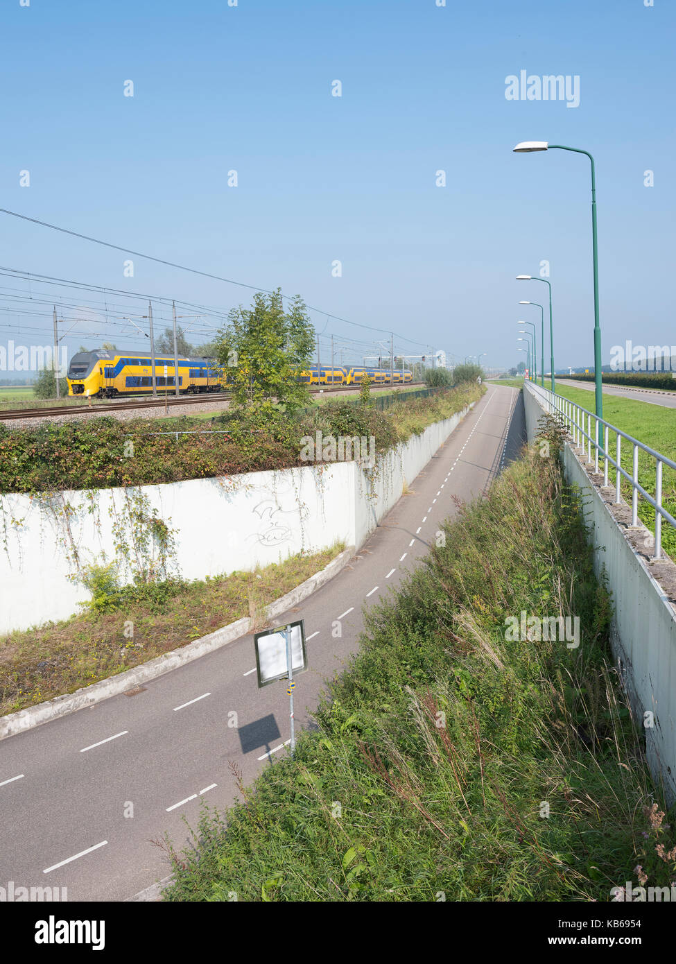 yellow and blue two story train passes fly over near breukelen between ...