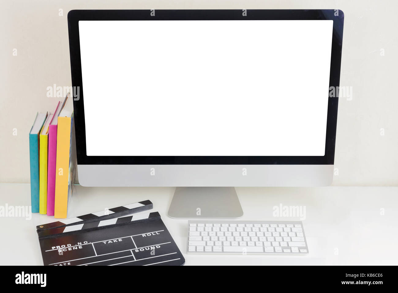 Workplace with monitor, keyboard, cinema clapboard, colorful books on ...