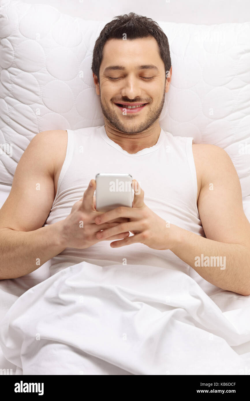 Young man lying in bed and using a phone Stock Photo - Alamy