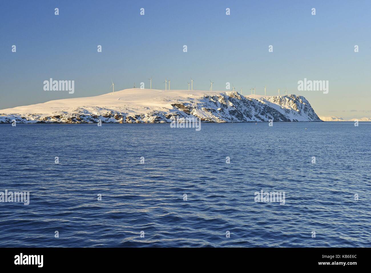 Light wavy ice blue sea water with the snow covered island Havøya and ...