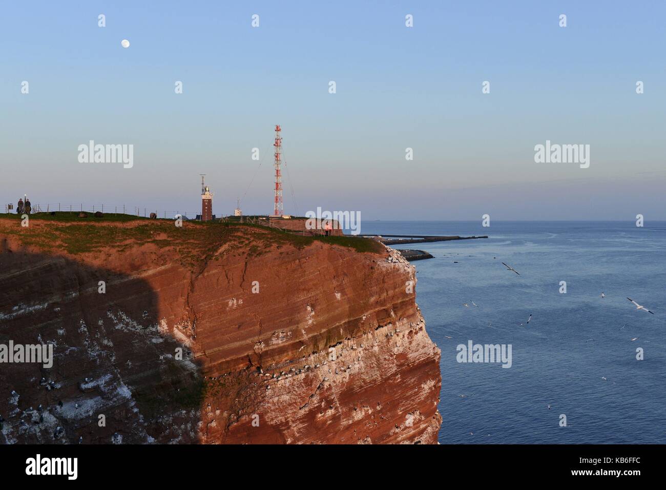 The moon above Heligoland's red rock coast with lighthouse and ...