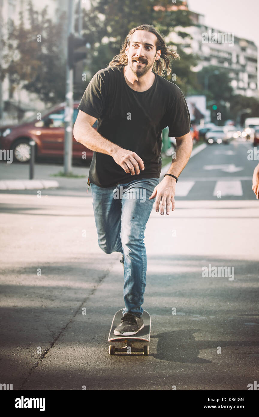 Pro skate rider ride skateboard in front of the car on the city road ...