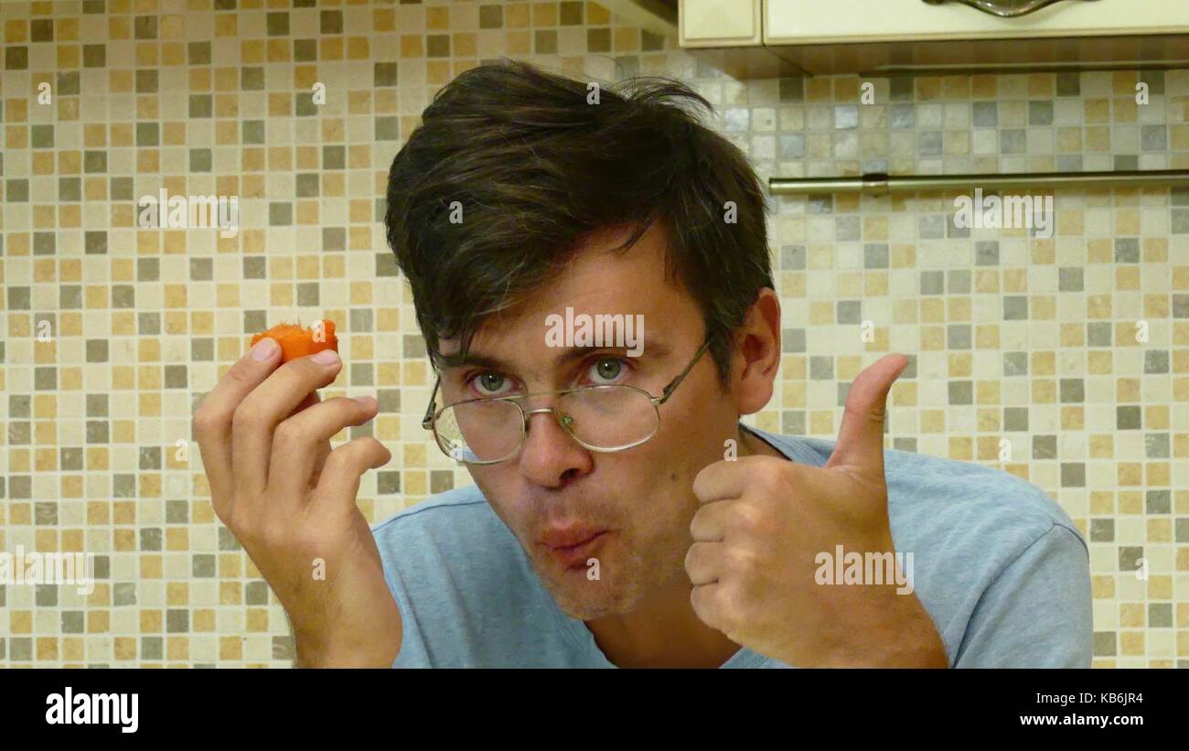 Adult man eating carrot on the morning indoors Stock Photo - Alamy