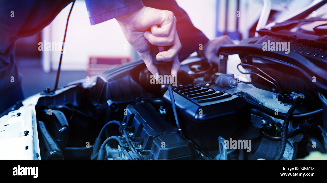 Mechanic using screwdriver on engine at the repair garage Stock Photo ...