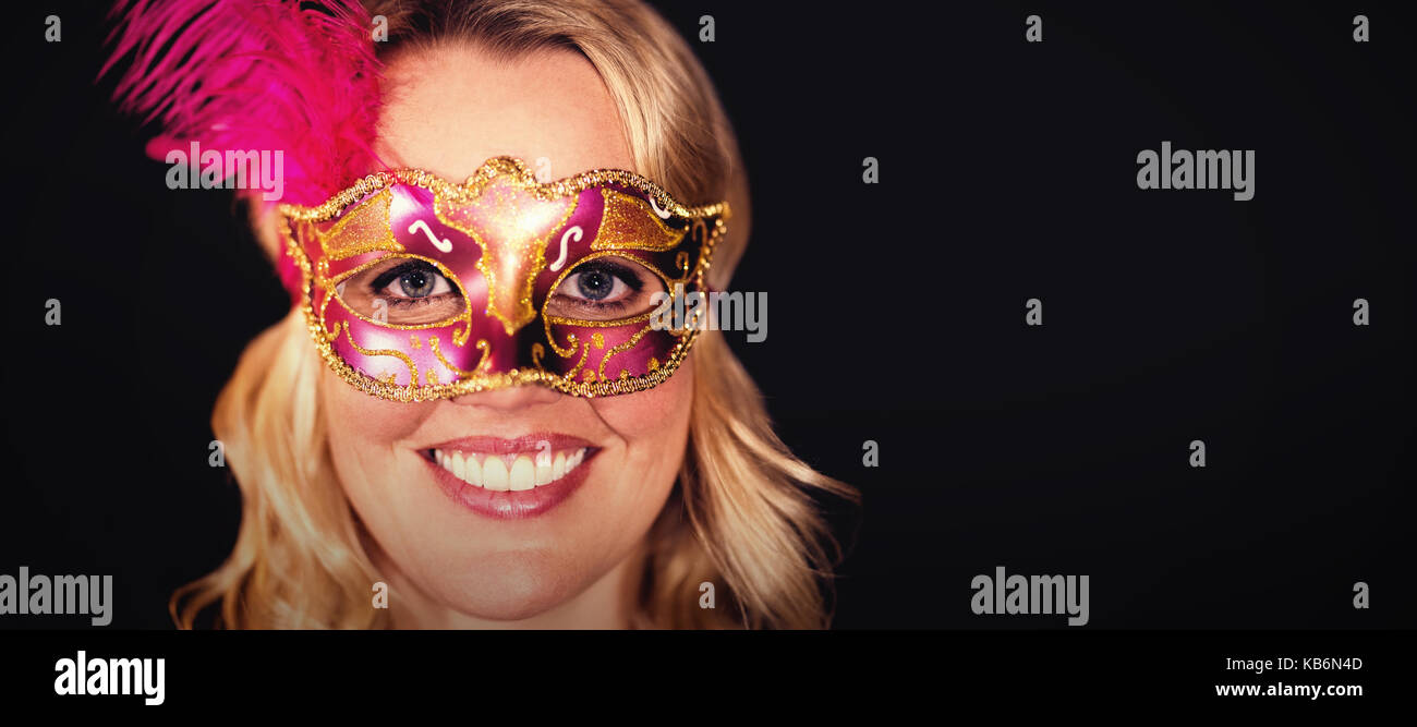 Portrait of happy woman in masquerade mask against black background ...