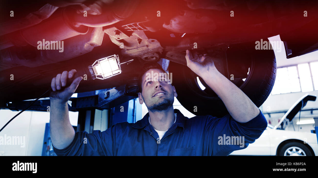Mechanic shining torch under car at garage Stock Photo - Alamy
