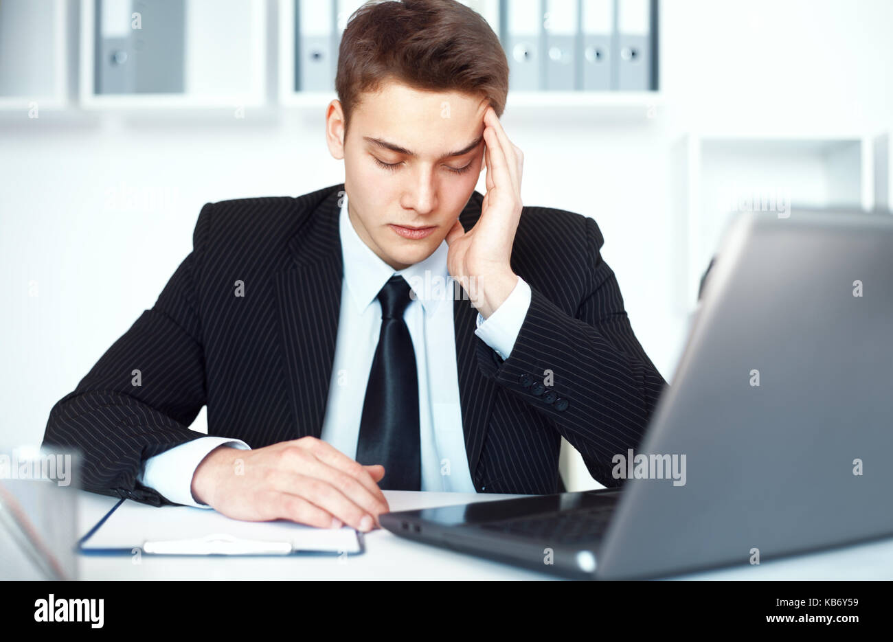 Tired young businessman with problems and stress at his workplace in ...