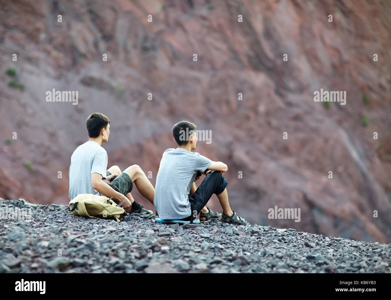 Two tourist young men sitting on rocky cliff and enjoying view Stock ...