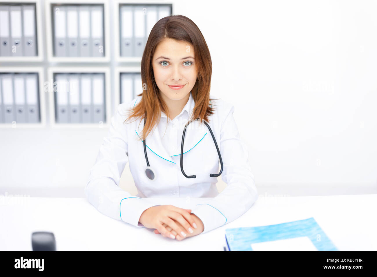 Portrait of young female doctor sitting at desk in hospital Stock Photo ...