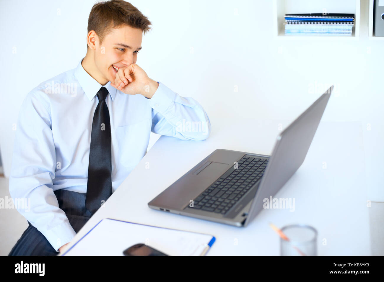 Portrait of young laughing businessman looking at the laptop screen at ...