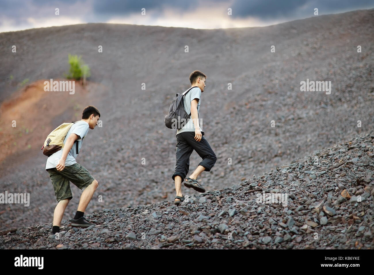 Two young tourist men walks on stones and rock slope Stock Photo - Alamy