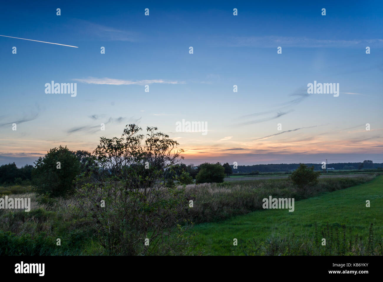 Sunset over the banks of a small river Stock Photo - Alamy