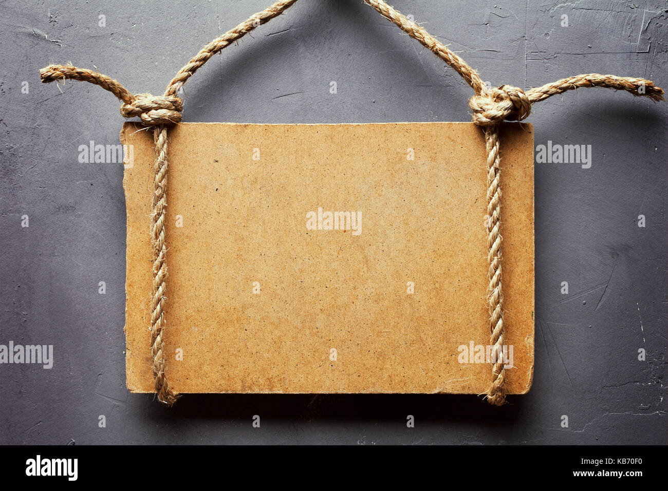 Wooden signboard with rope hanging on gray textured wall Stock Photo ...