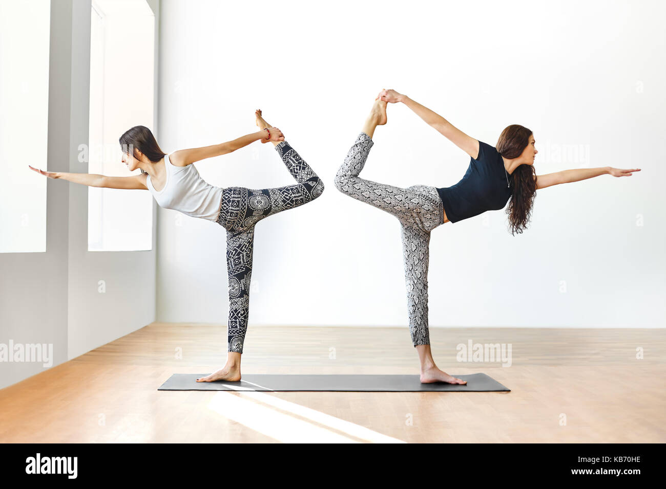 Two young women doing yoga asana lord of the dance pose. Natarajasana ...