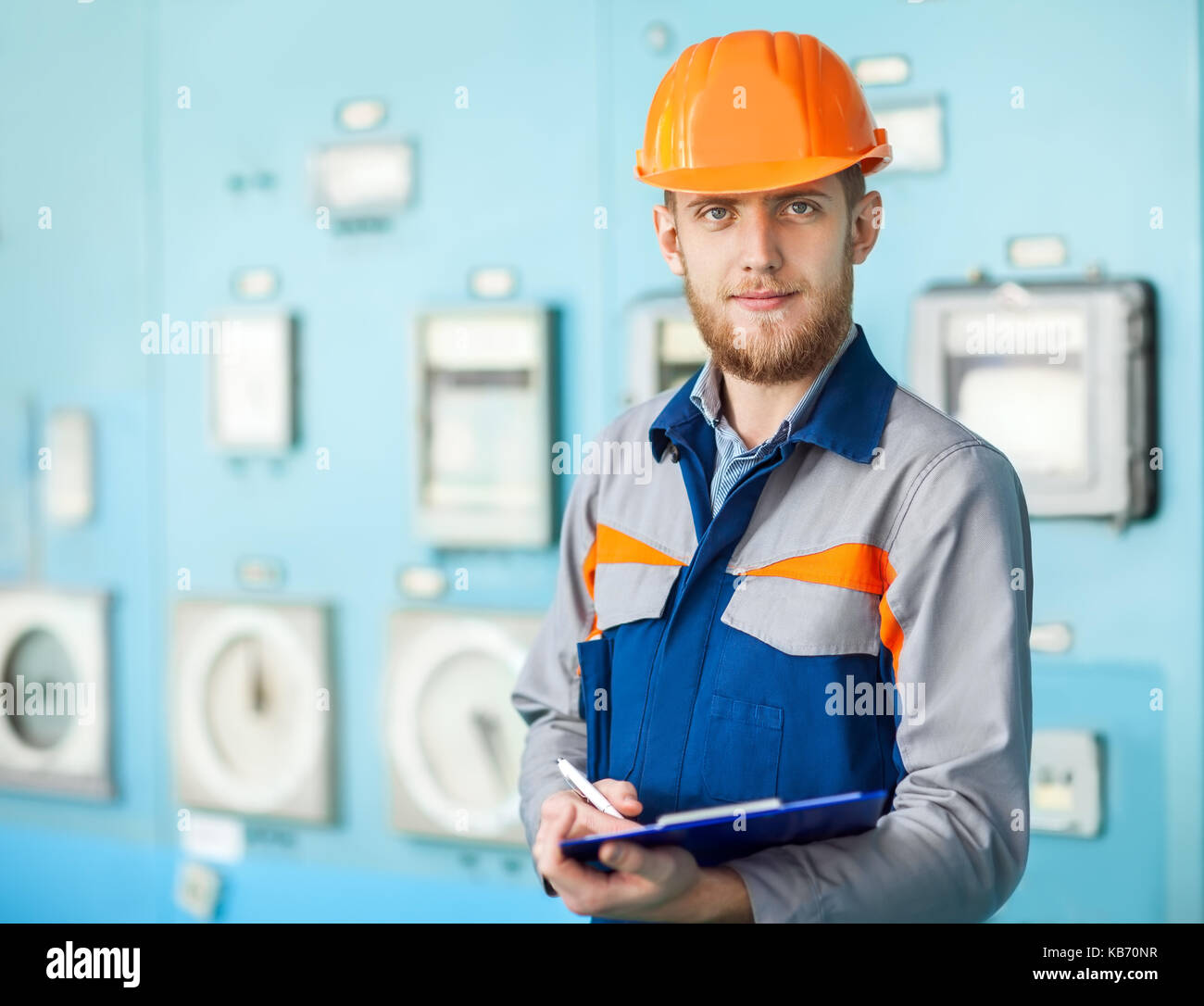 Portrait of young engineer taking notes at control room in factory ...