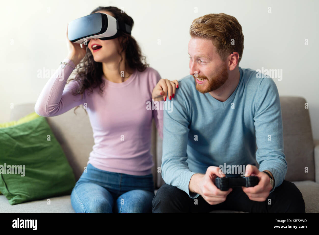 Happy young couple playing video games with virtual reality headsets ...