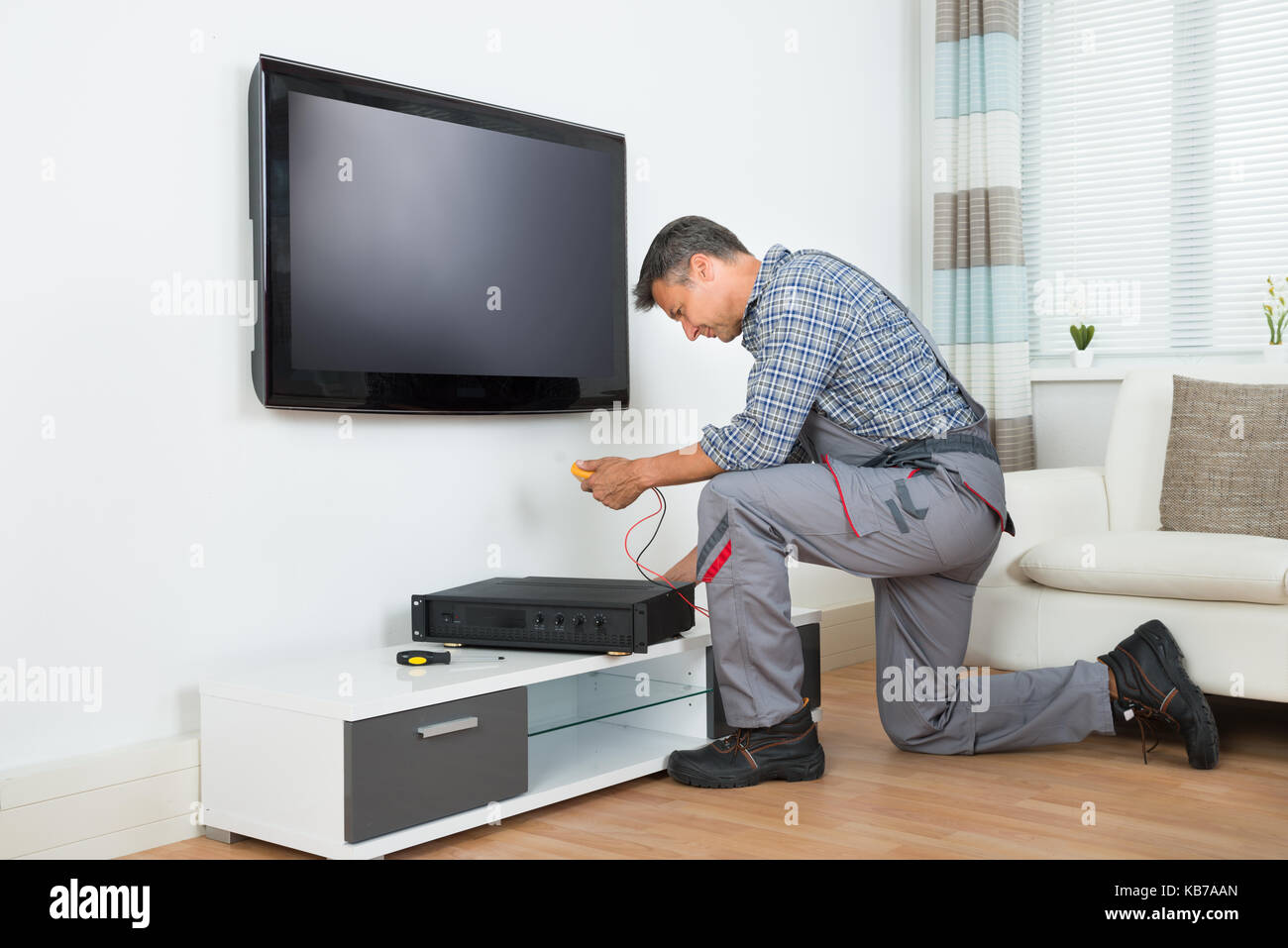 Full length of male technician installing TV set top box at home Stock ...