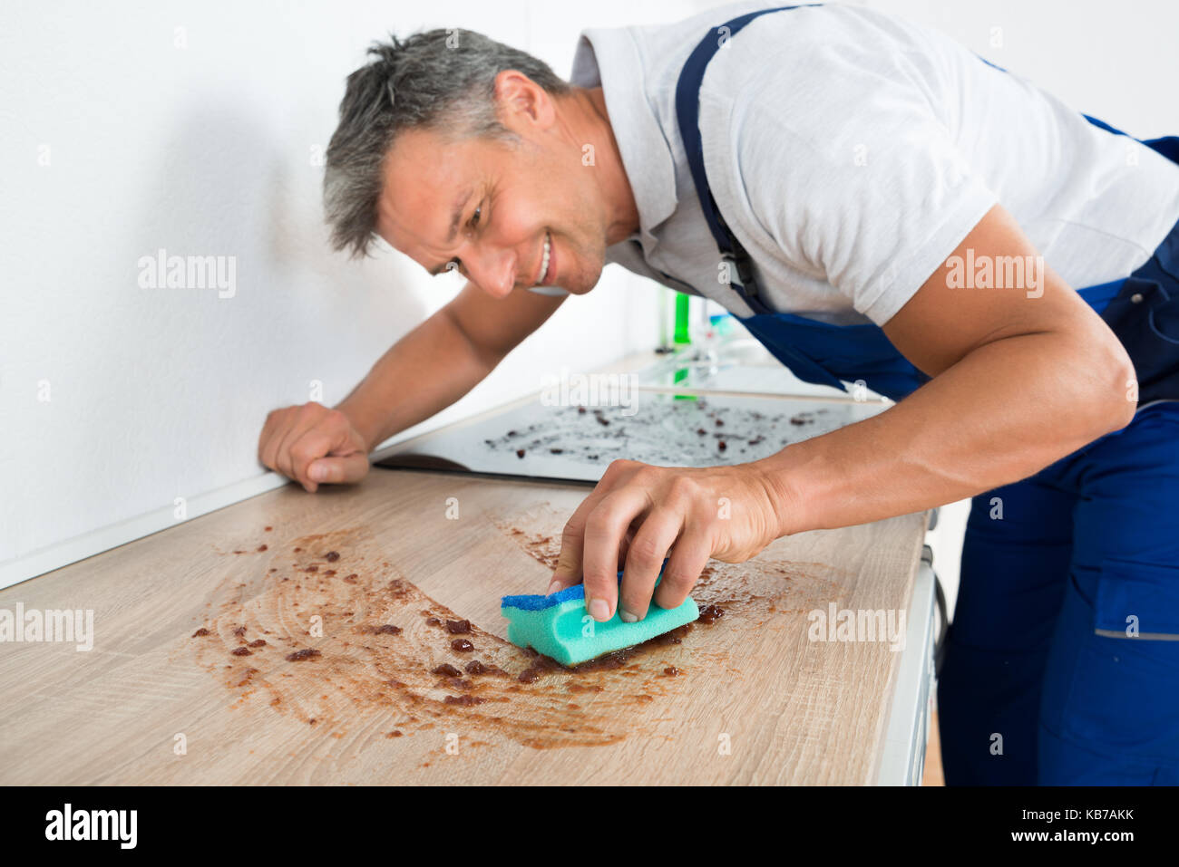 Happy mature man cleaning kitchen counter with sponge Stock Photo - Alamy