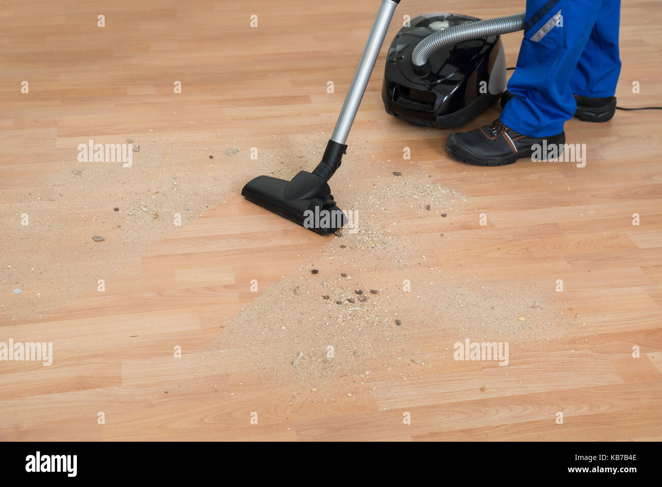 Low section of male janitor cleaning floor with vacuum cleaner in ...