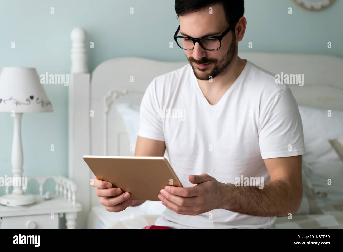 Young handsome man using digital tablet on bed Stock Photo - Alamy