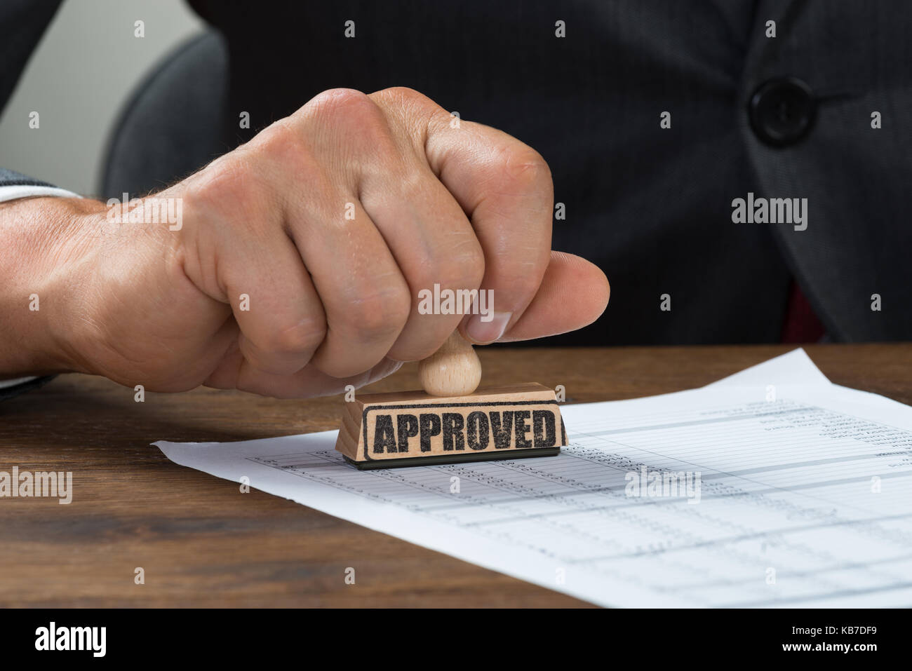 Cropped image of businessman stamping document marked with approved at ...