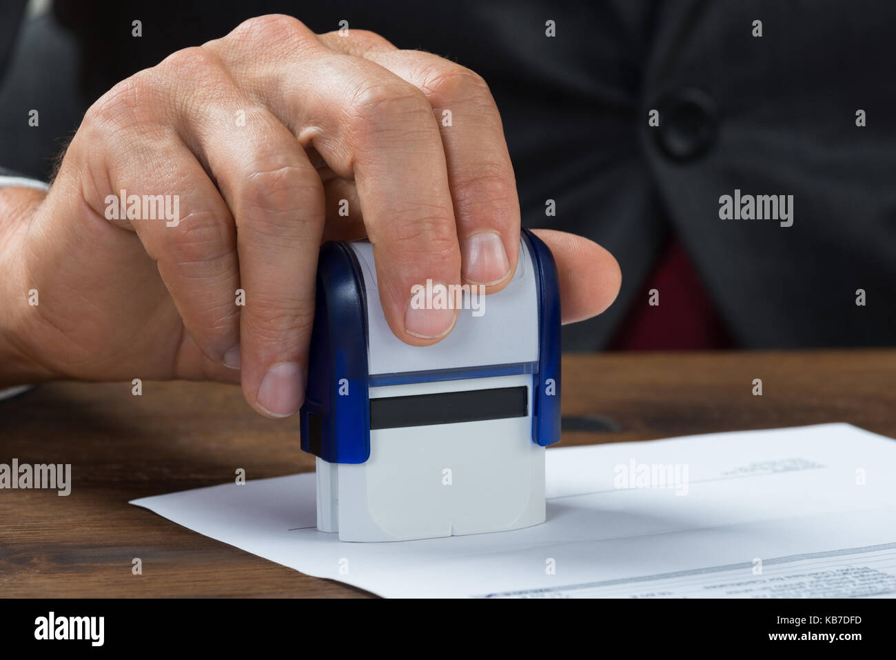 Cropped image of businessman stamping document at desk Stock Photo - Alamy