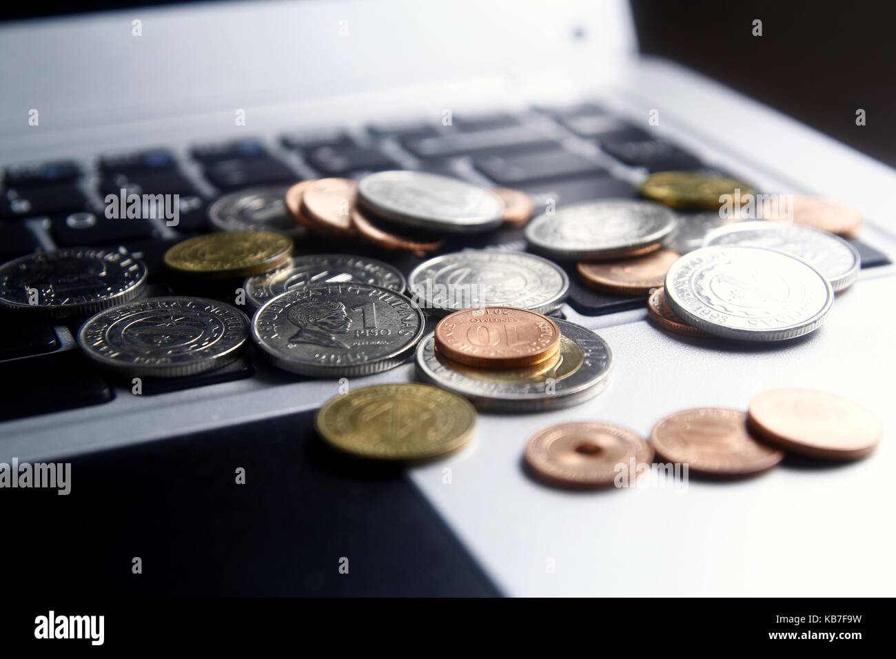 Photo of different coins on a laptop computer keyboard Stock Photo - Alamy