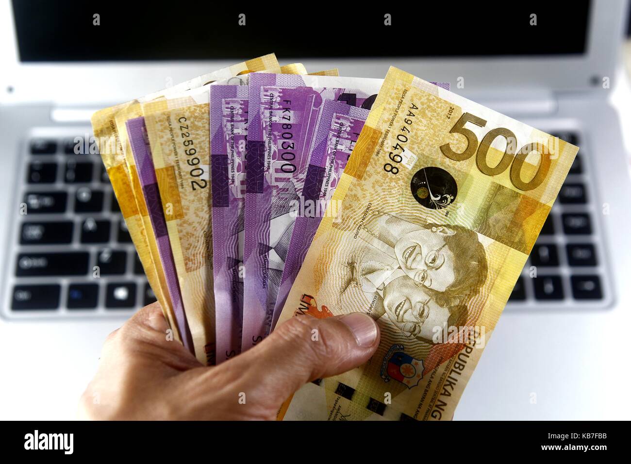Photo of a hand holding money and a laptop computer Stock Photo - Alamy