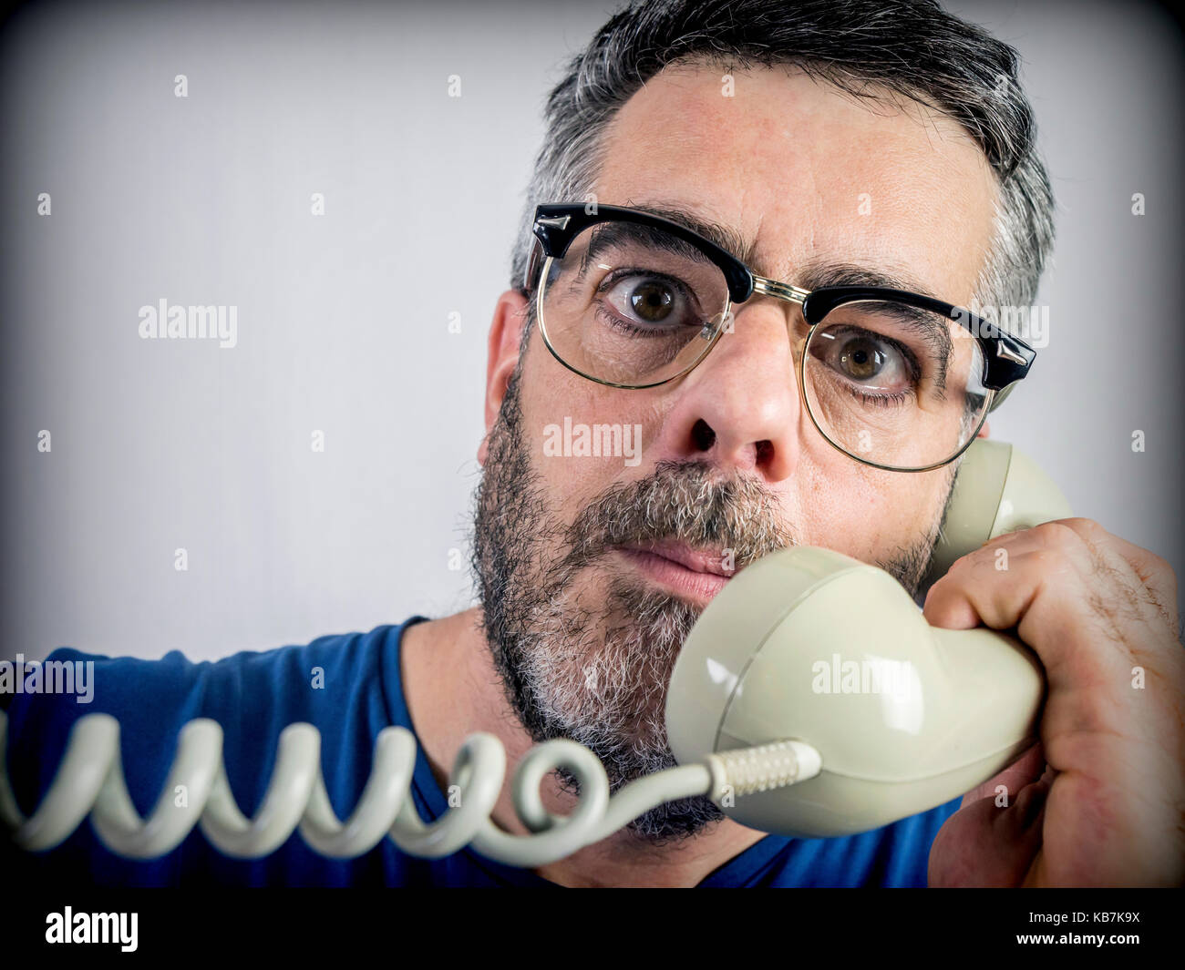 Man with surprised face talking on vintage phone Stock Photo - Alamy