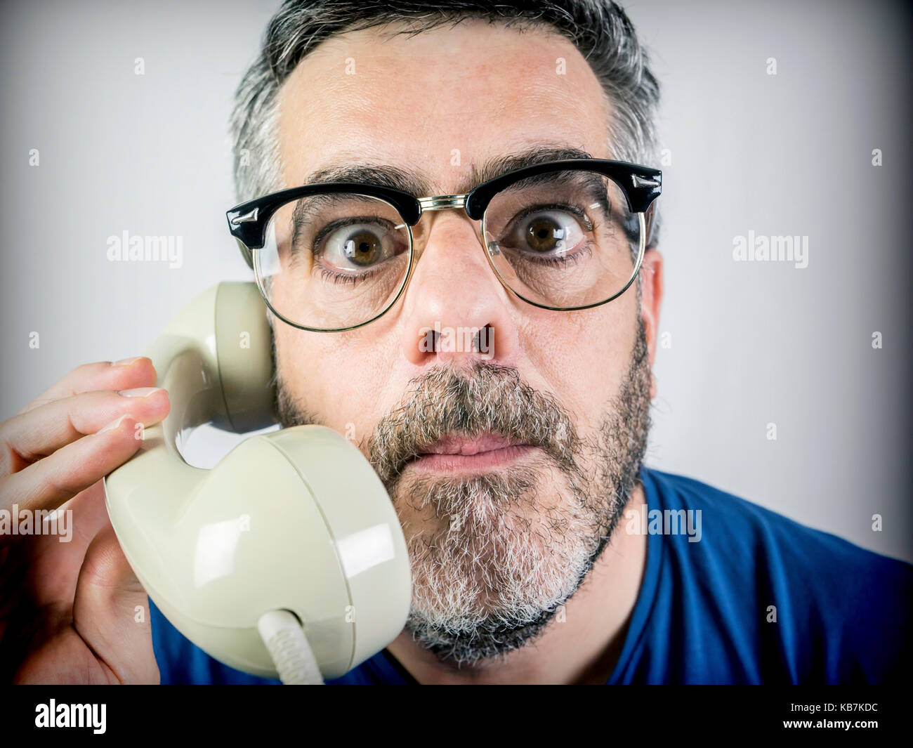 Man with surprised face talking on vintage phone Stock Photo - Alamy