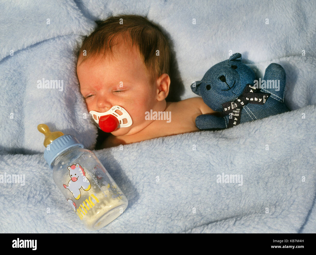 A two week old baby girl sucking on a pacifier as she sleeps Stock ...