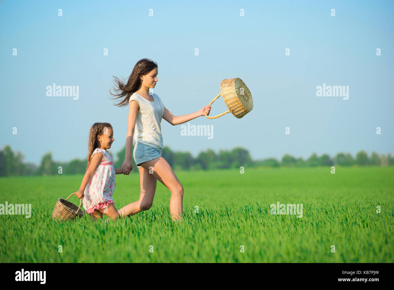Young happy girls running witch baskets at green wheat field Stock ...