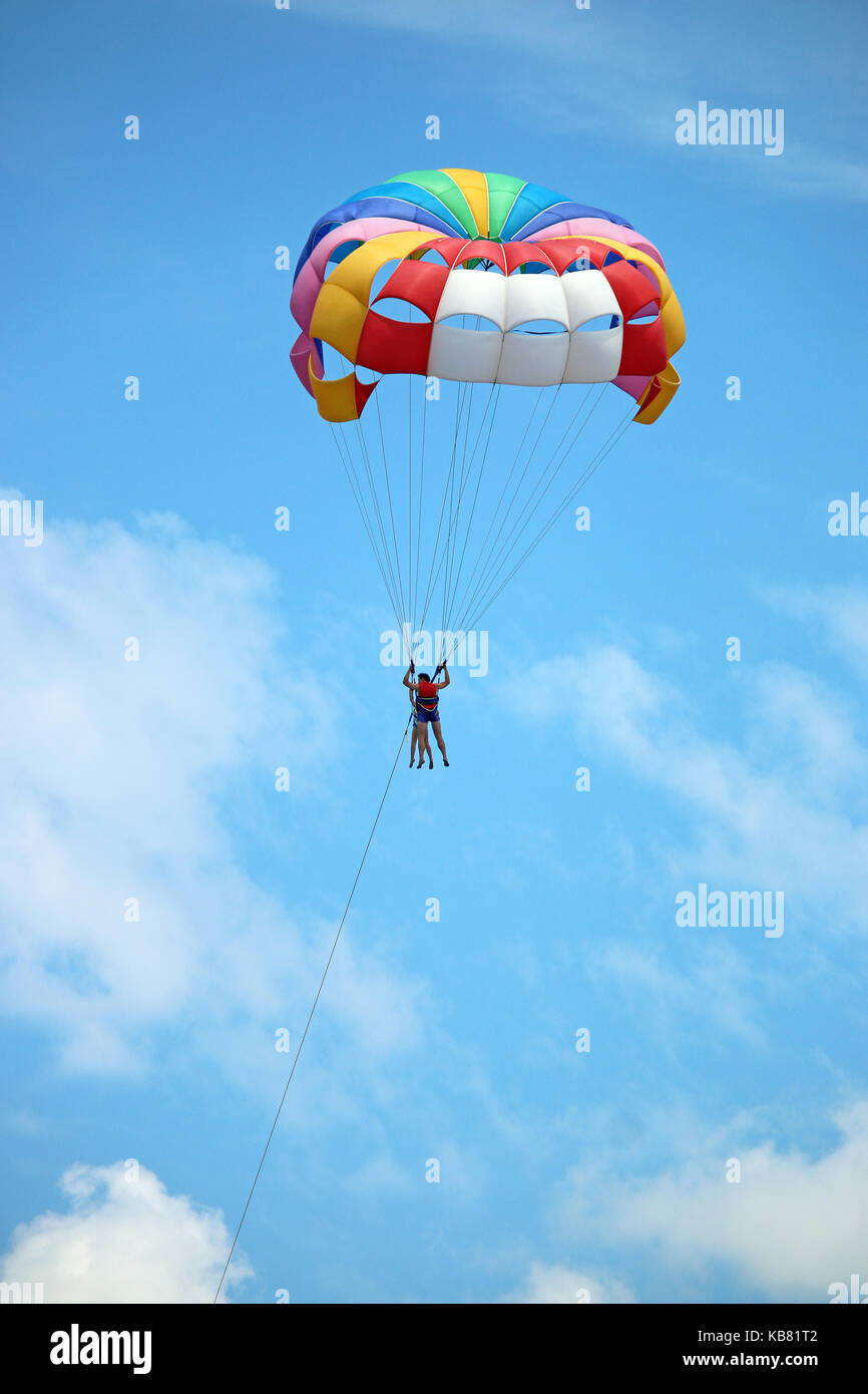 Two people parasailing with parachute on blue sky with clouds Stock ...