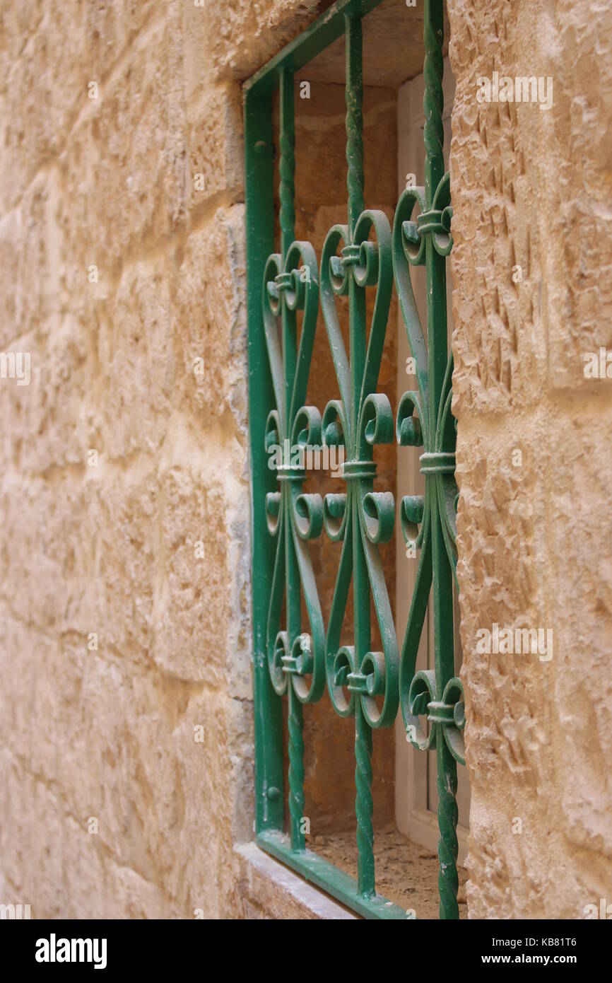 A close up of painted green ironwork decorative bars on a window, in ...