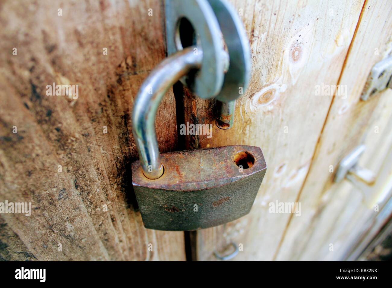 Open a padlock with traces of rust hanging on the door Stock Photo - Alamy