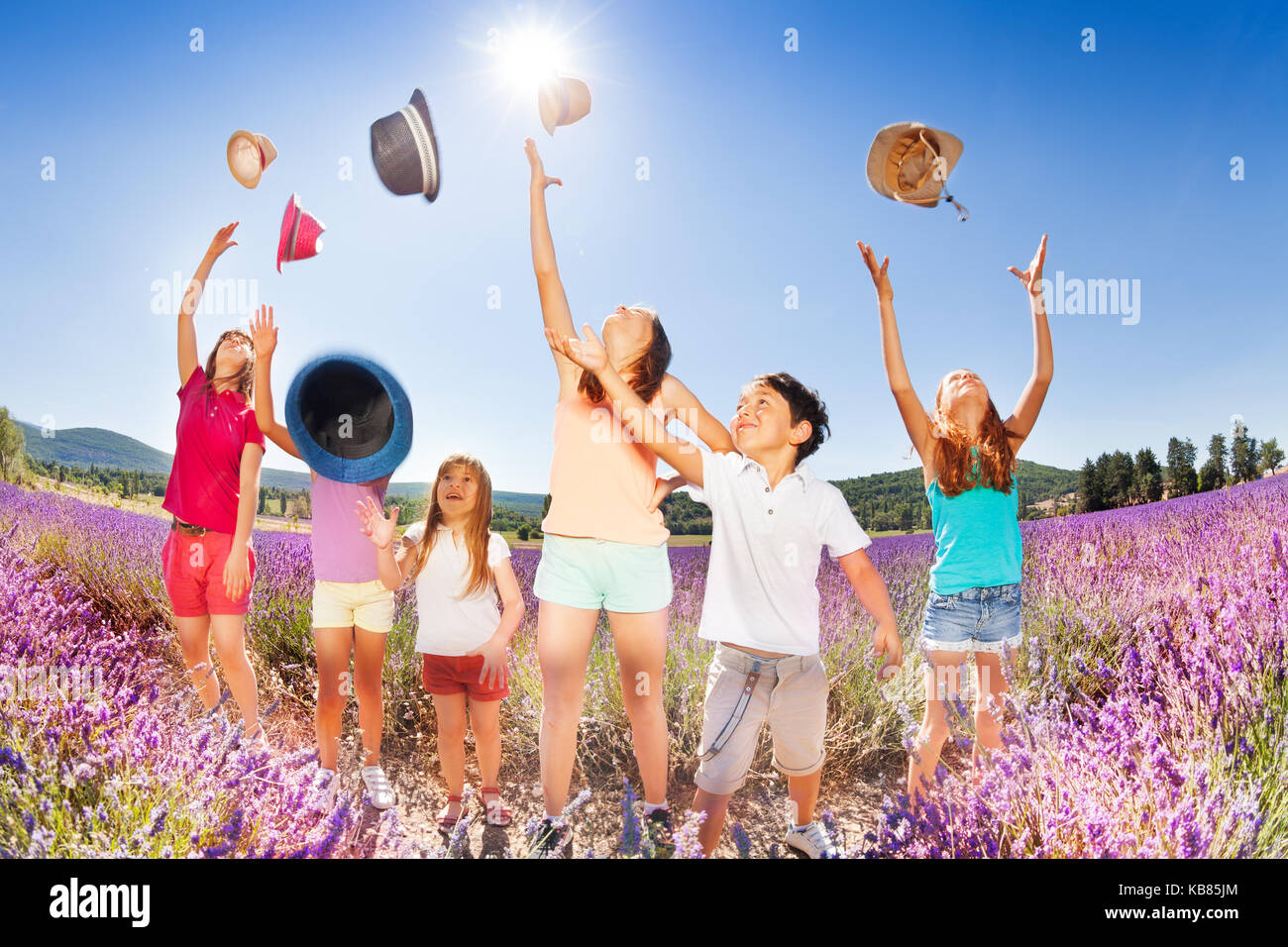 Happy kids tossing up hats over blue sky in summer Stock Photo - Alamy