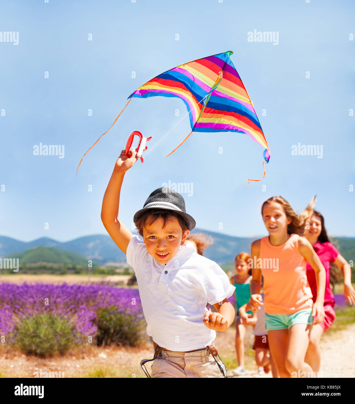 Happy boy flying rainbow kite with his friends Stock Photo - Alamy