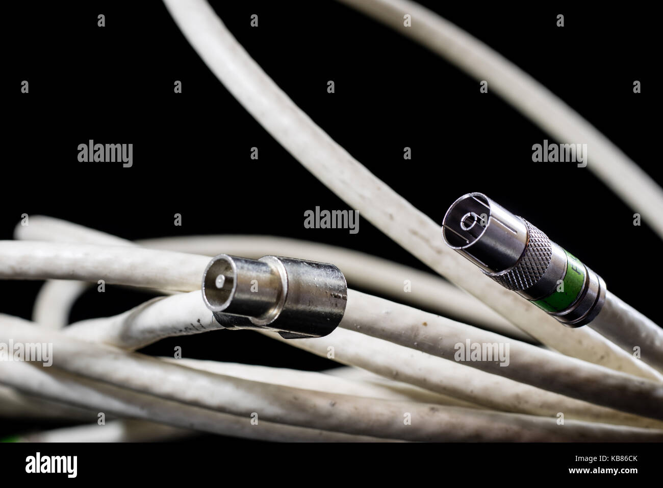 Old entangled cables, electronics and old cable connectors on a black table. Black background ...