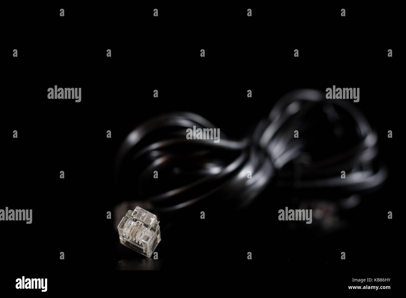 Old entangled cables, electronics and old cable connectors on a black table. Black background ...