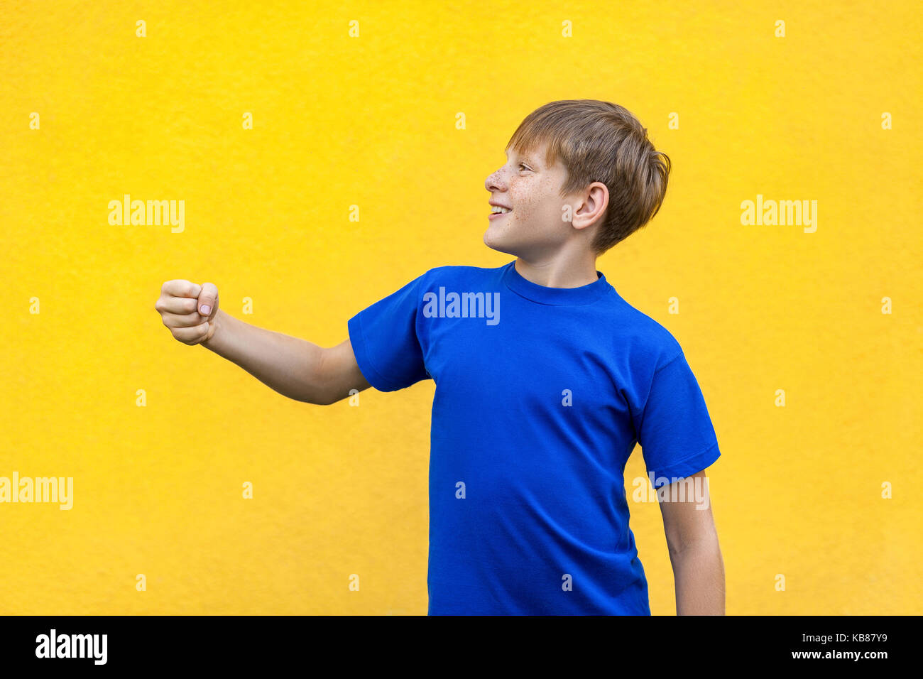 Funny freckled boy holding imaginary object. Studio shot, isolated on ...