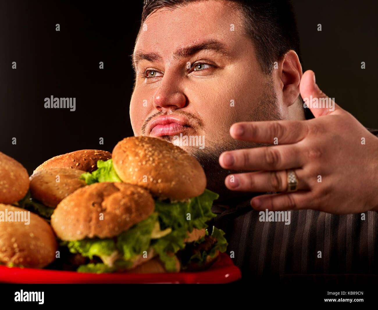 Fat man eating fast food hamberger. Breakfast for overweight person ...