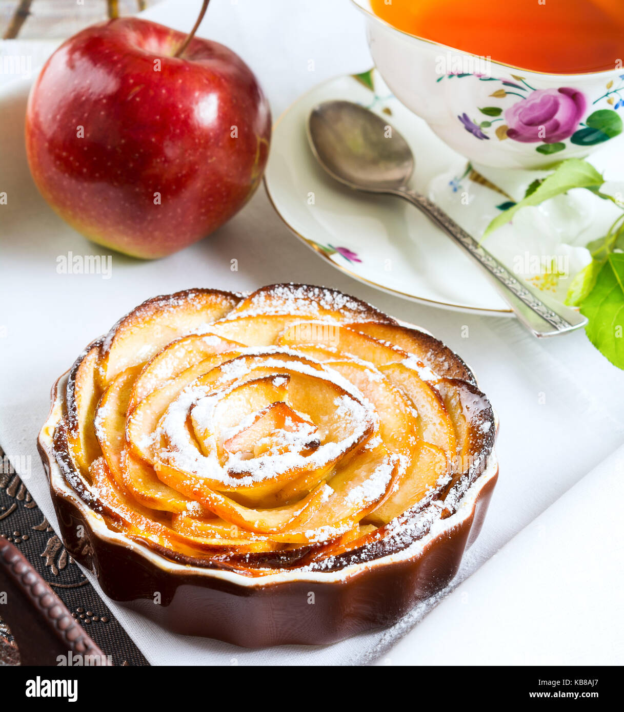 Apple rose shaped pie and cup of tea on the serving tray. Breakfast tea ...