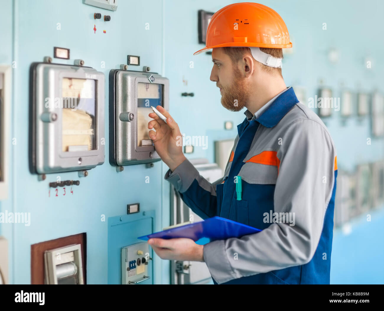 Portrait of young engineer taking notes at control room in factory ...