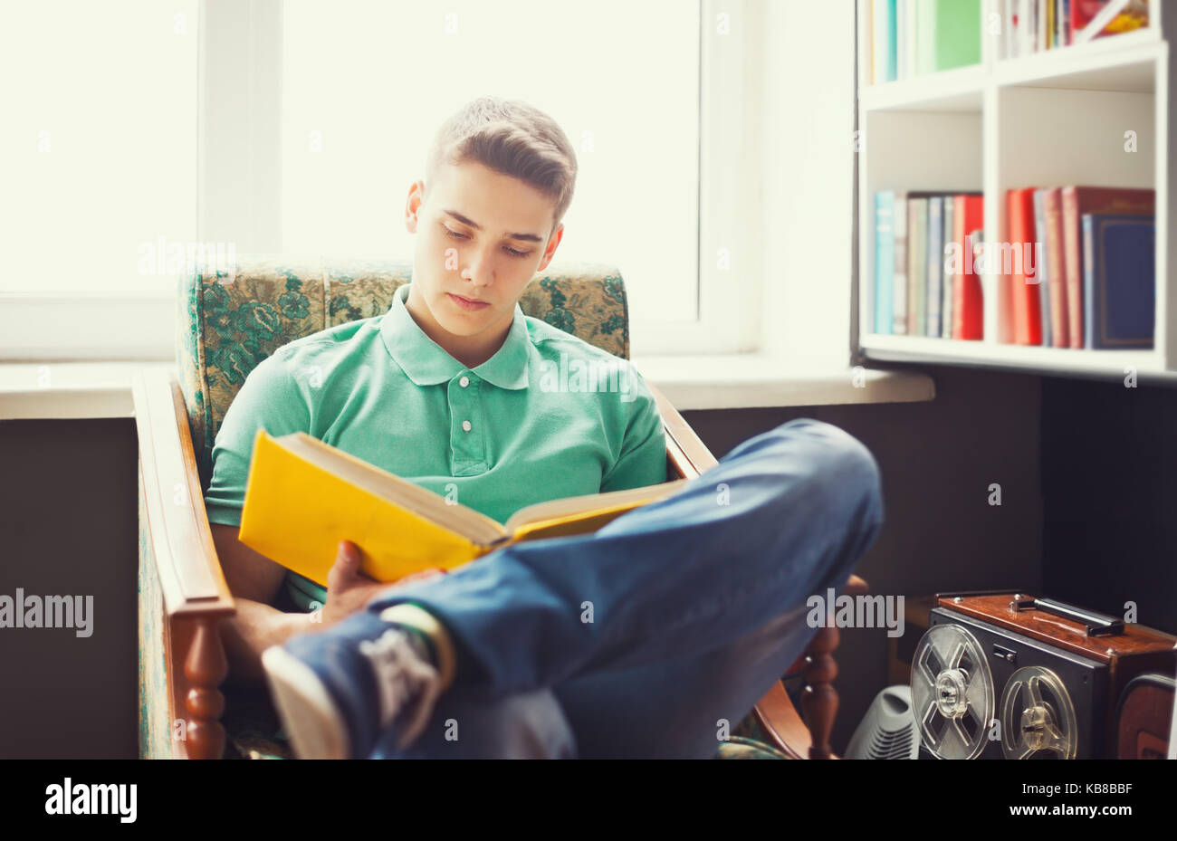 Student at home sitting on chair and reading book Stock Photo - Alamy