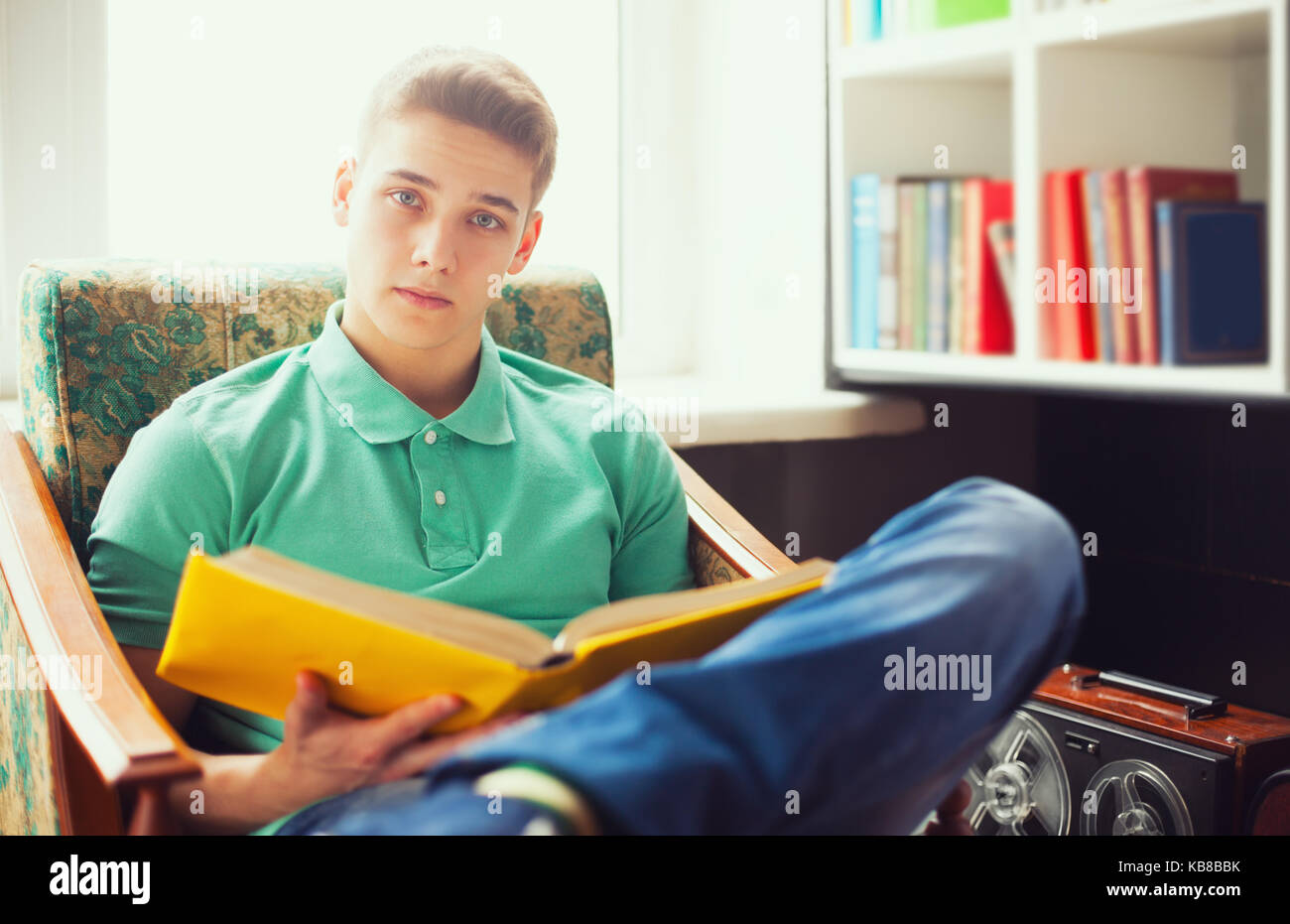 Student at home sitting on chair and reading book Stock Photo - Alamy