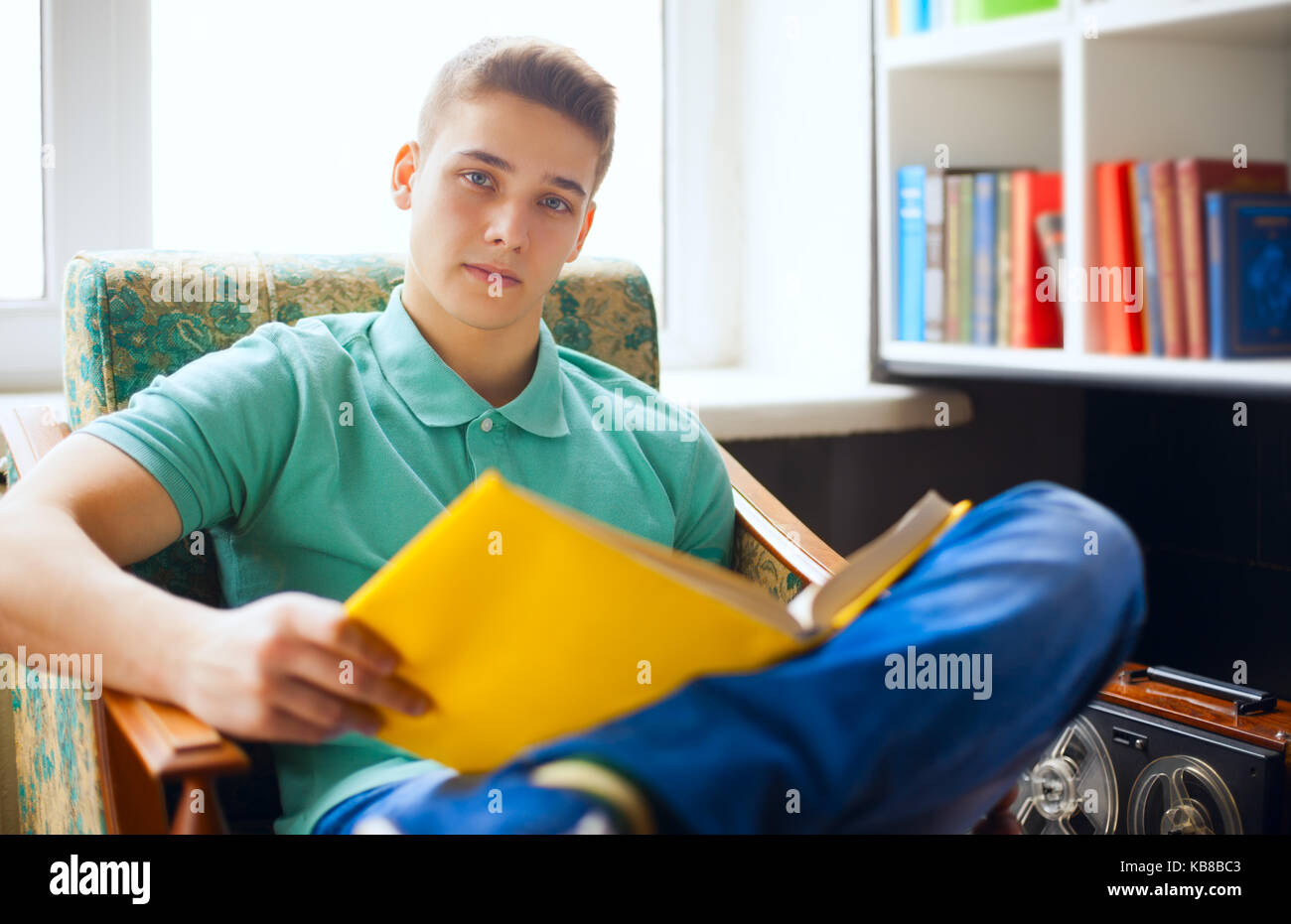 Student at home sitting on chair and reading book Stock Photo - Alamy