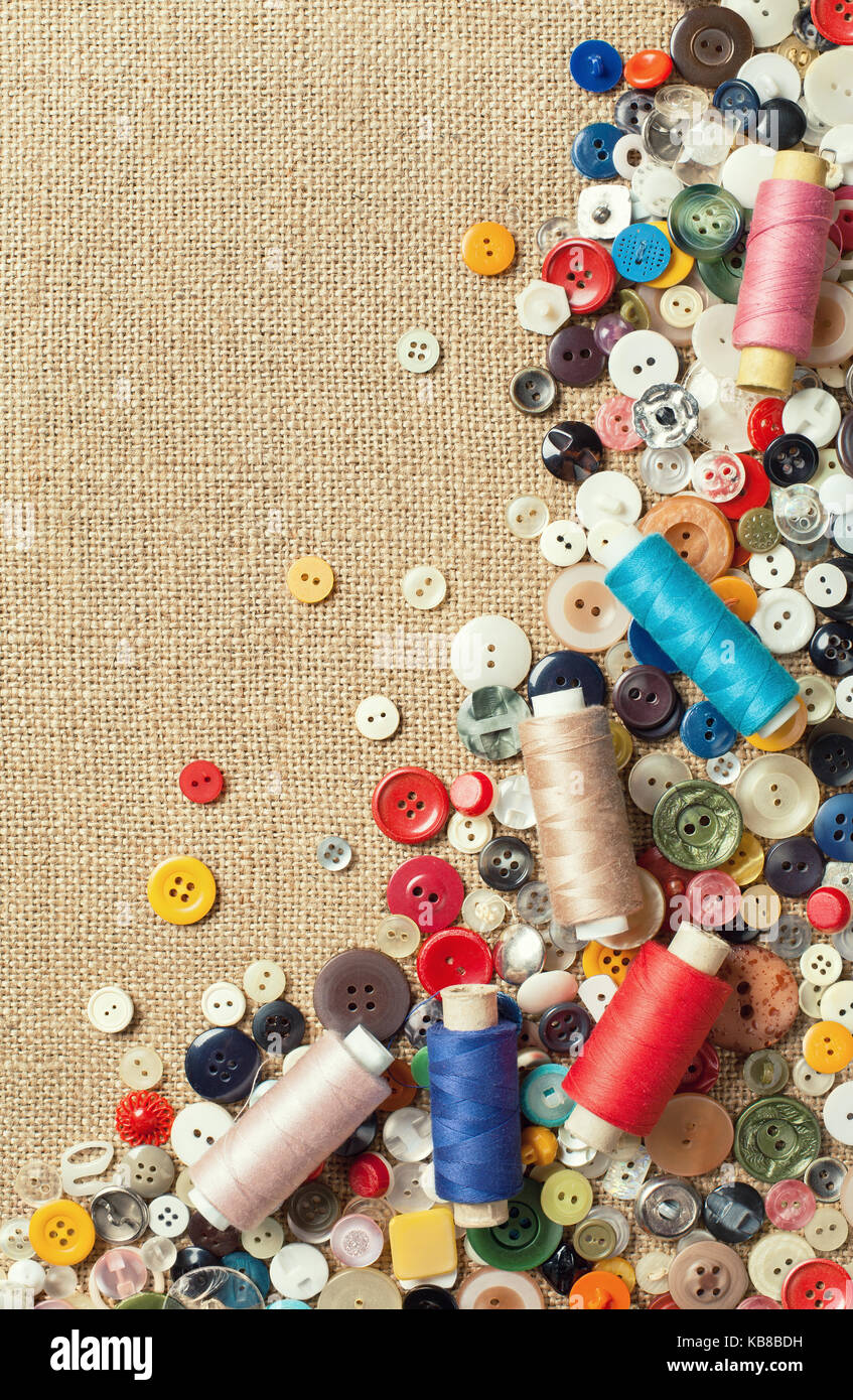 Colourful sewing buttons and spools of threads on fabric texture ...